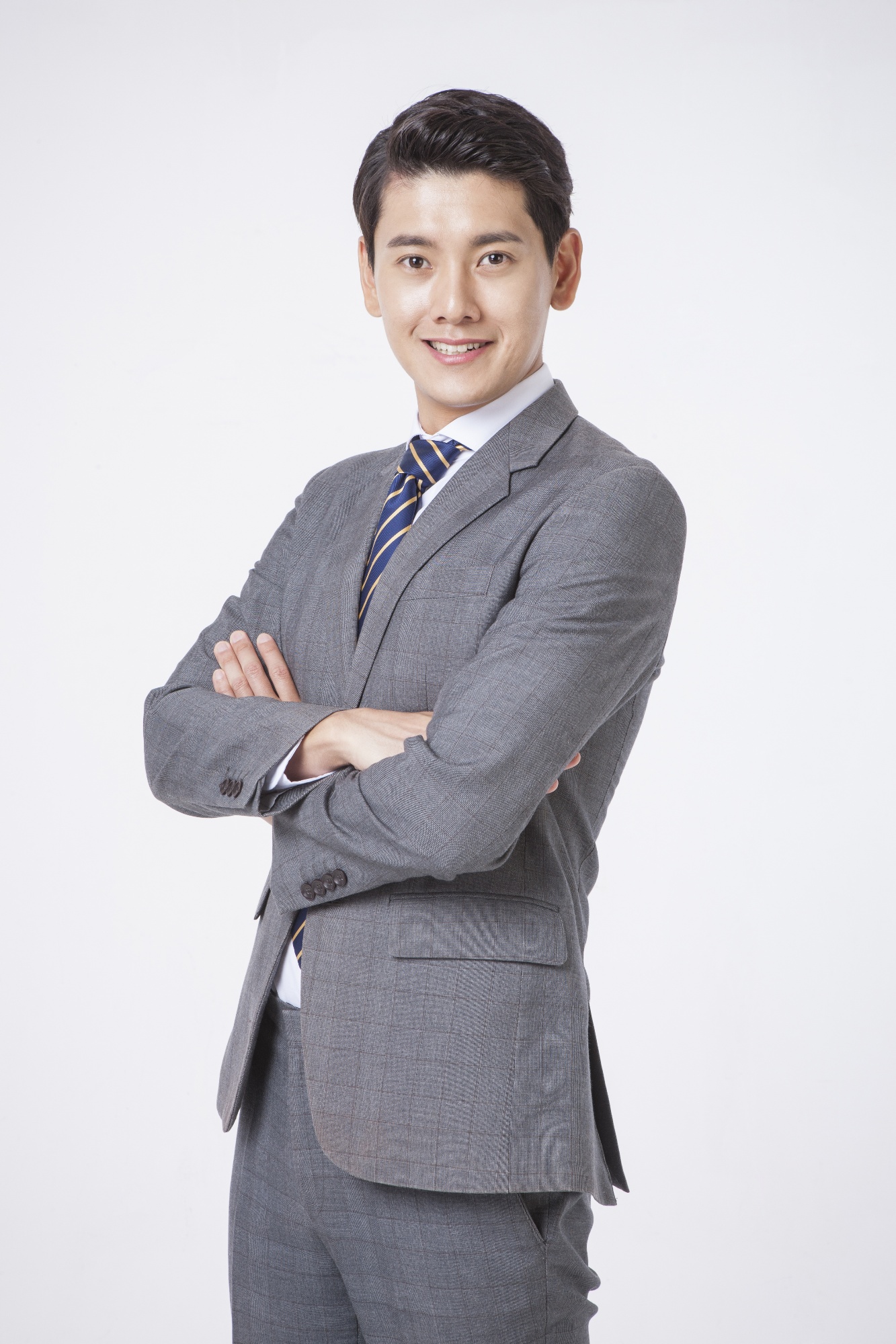 穿着灰色西装的年轻微笑男子折着双臂盯着前面Young smiling man in gray suit folding his arms ...